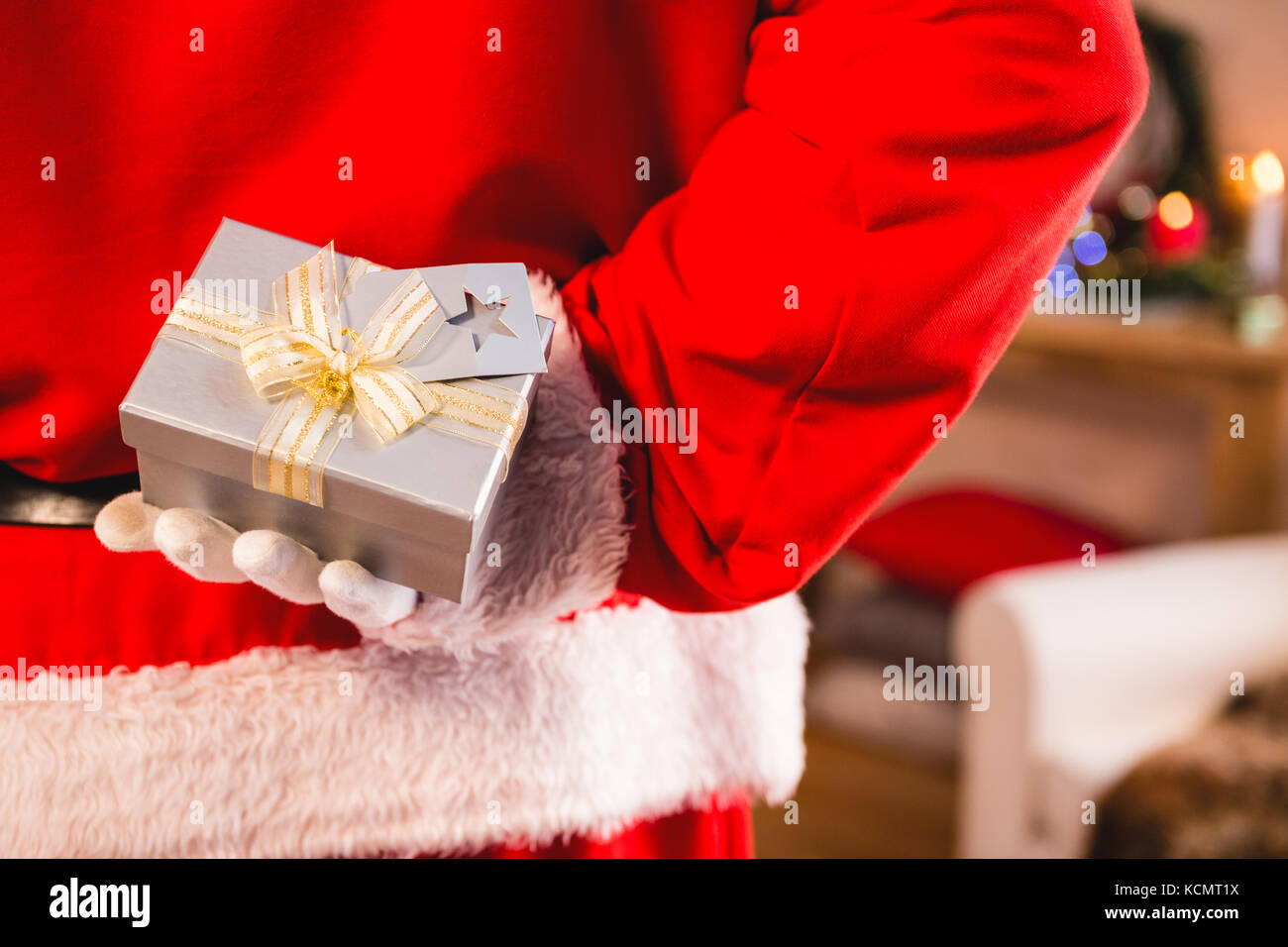 Rear view of santa claus hiding a gift box behind his back Stock Photo ...