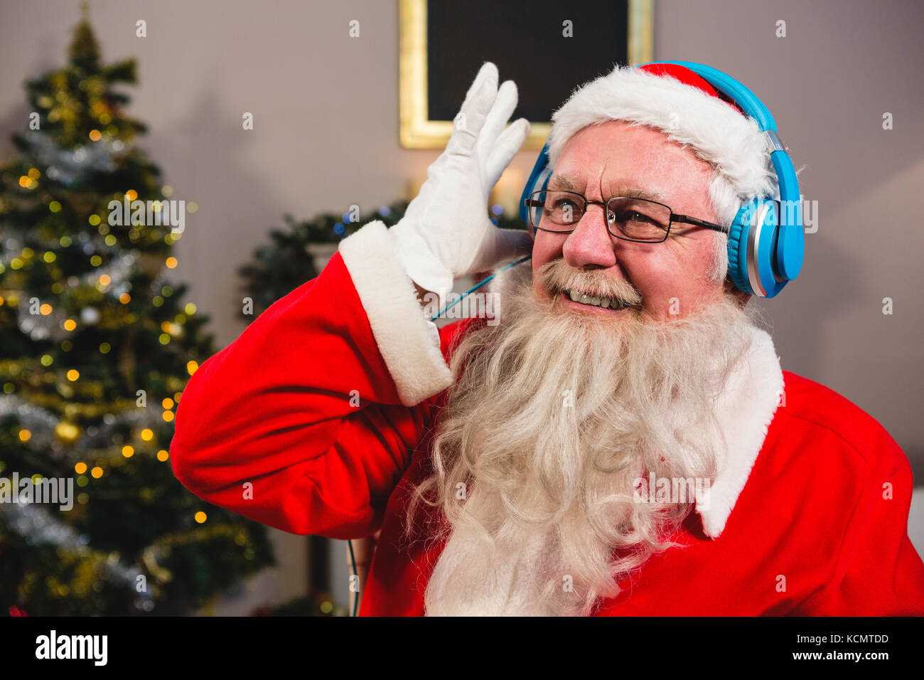 Smiling santa claus listening to music on headphones at home Stock ...