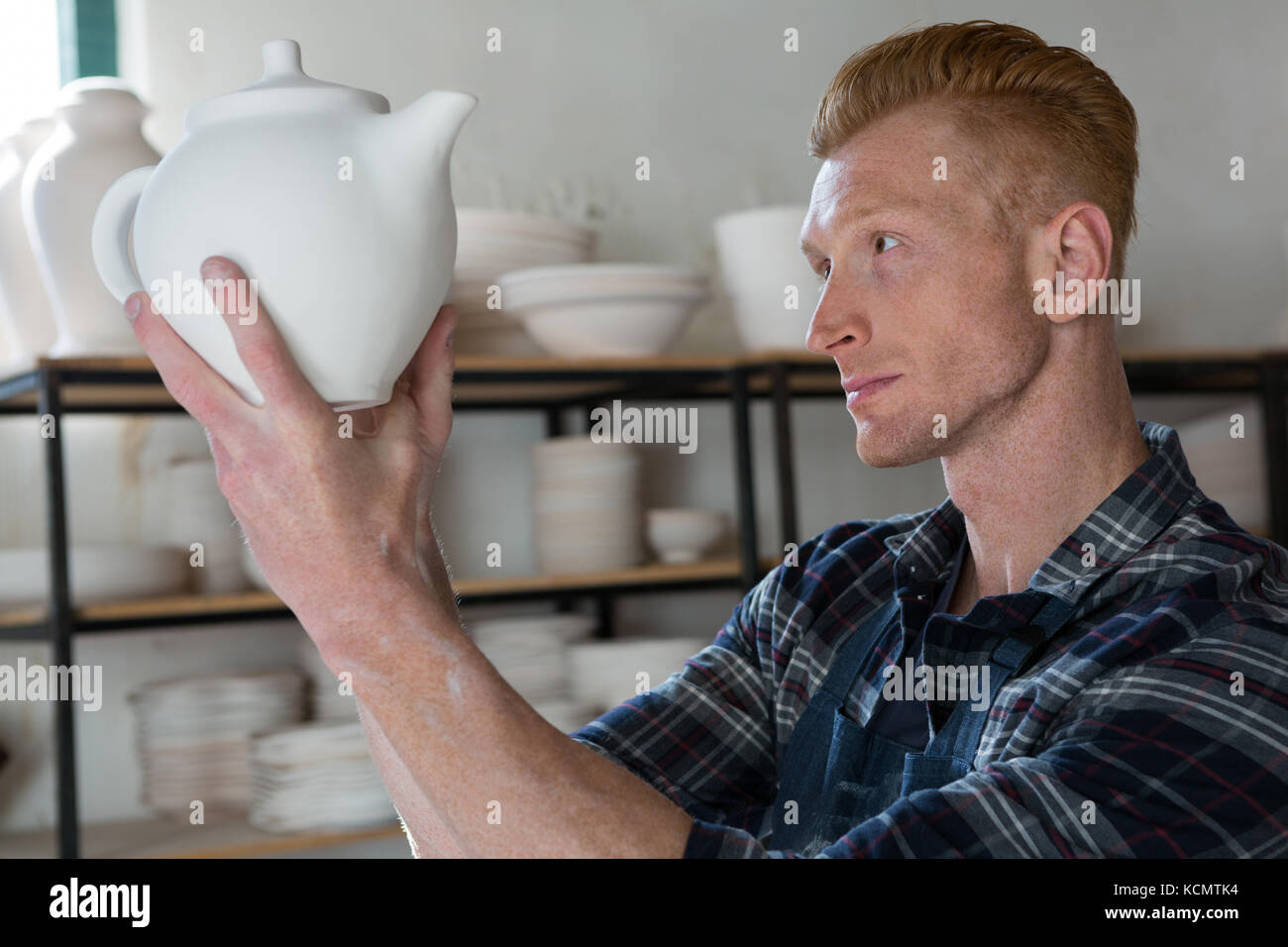 Male potter examining a teapot in pottery workshop Stock Photo - Alamy