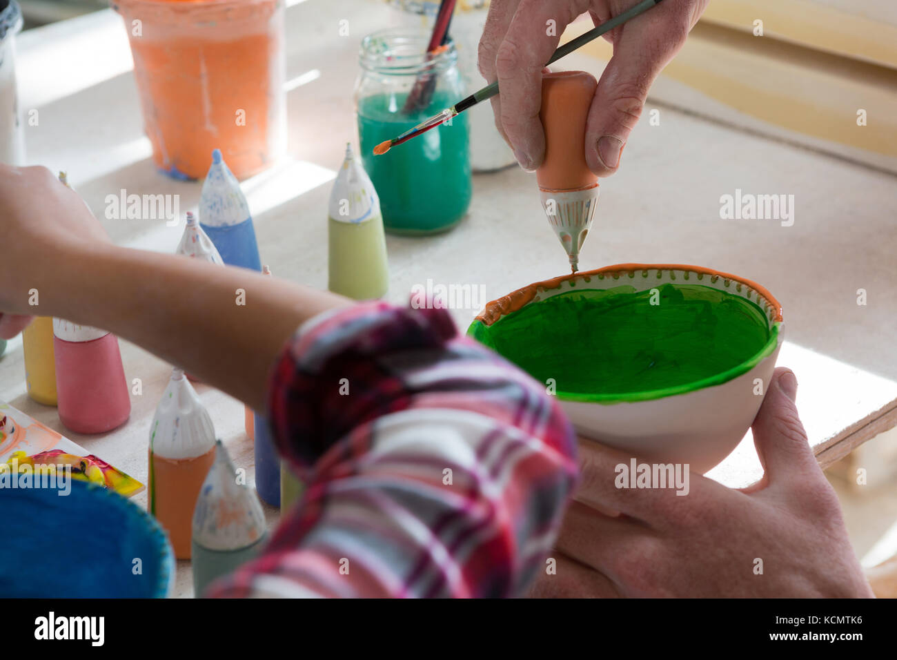 Male potter and girl painting bowl in pottery workshop Stock Photo - Alamy