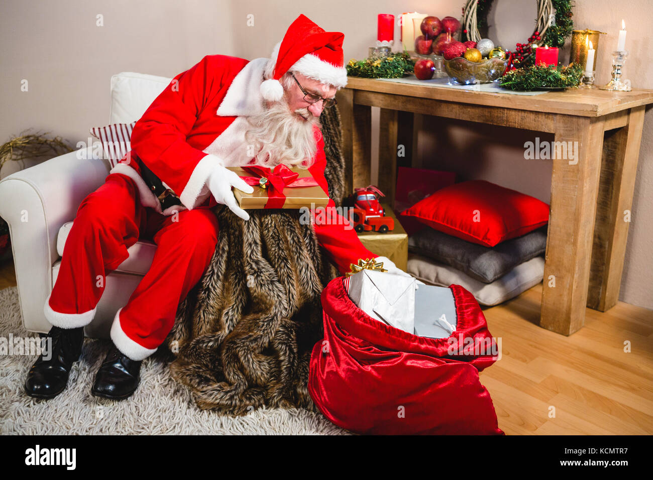 Santa claus removing gift from gift sack in living room at home during ...