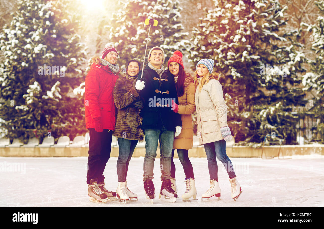 happy friends with smartphone on ice skating rink Stock Photo - Alamy