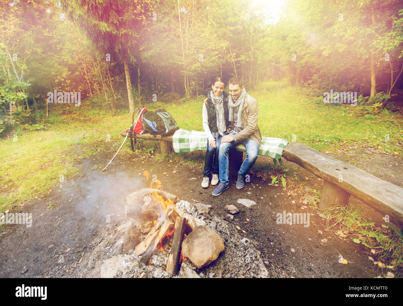 happy couple sitting on bench near camp fire Stock Photo - Alamy