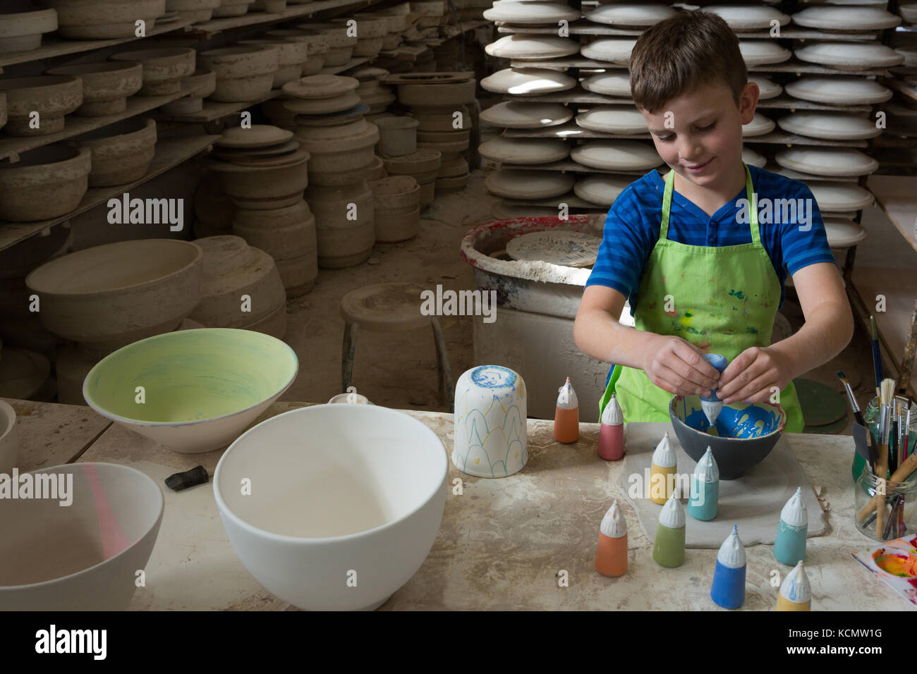 Attentive boy painting a bowl in pottery shop Stock Photo - Alamy