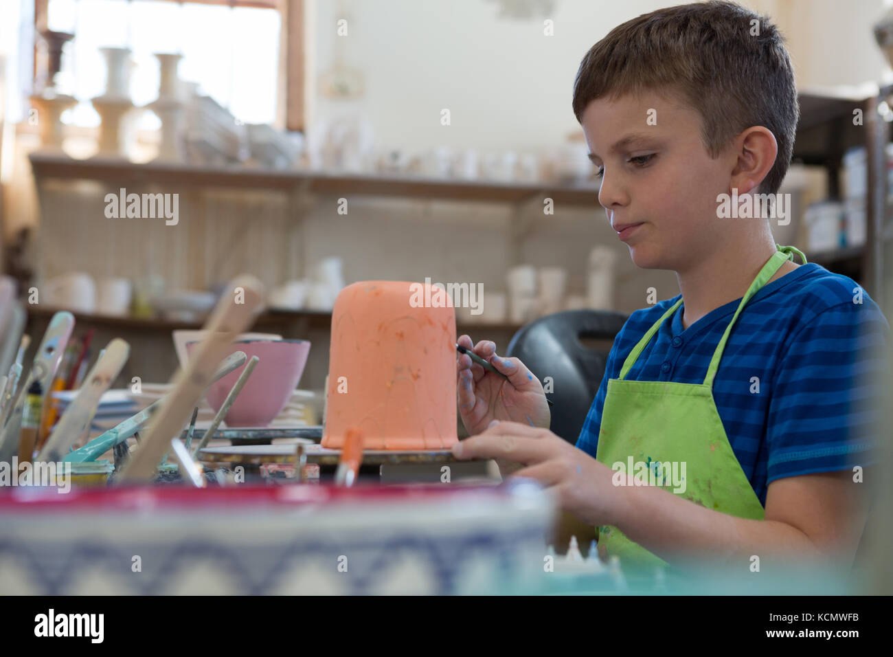 Attentive boy painting a bowl in pottery shop Stock Photo - Alamy