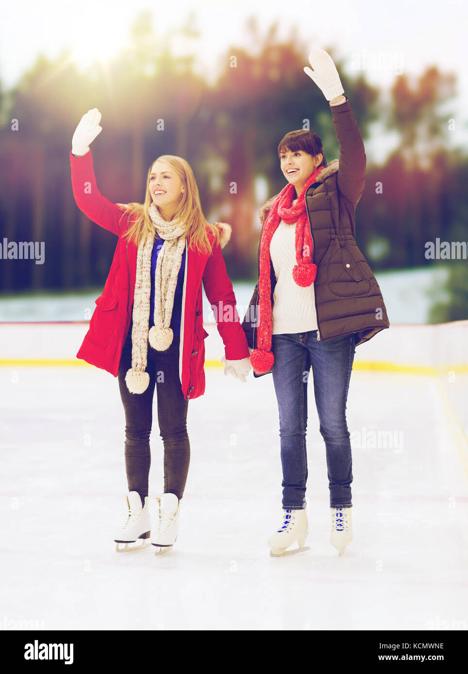 women or friends waving hands on skating rink Stock Photo - Alamy
