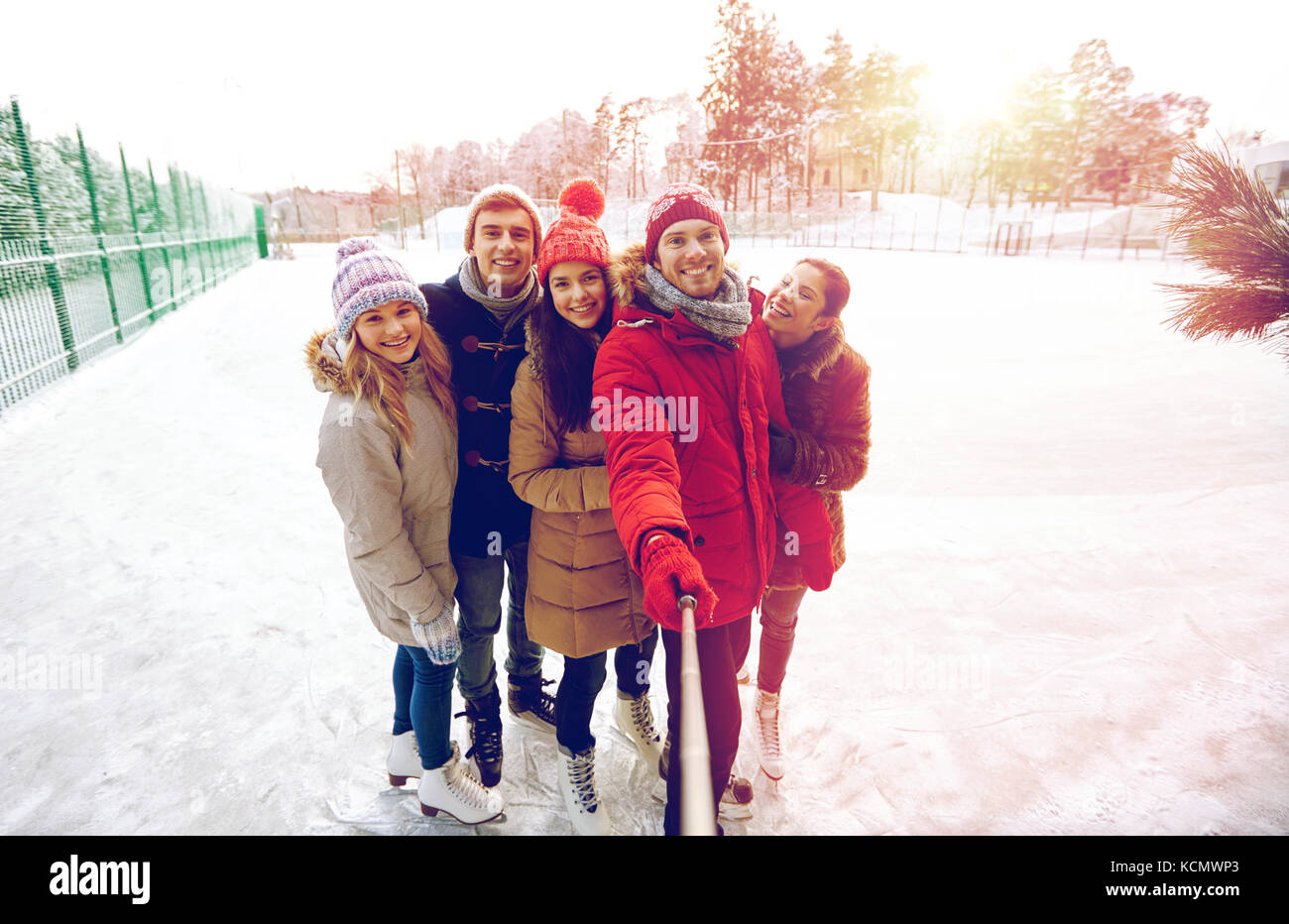 happy friends with smartphone on ice skating rink Stock Photo - Alamy