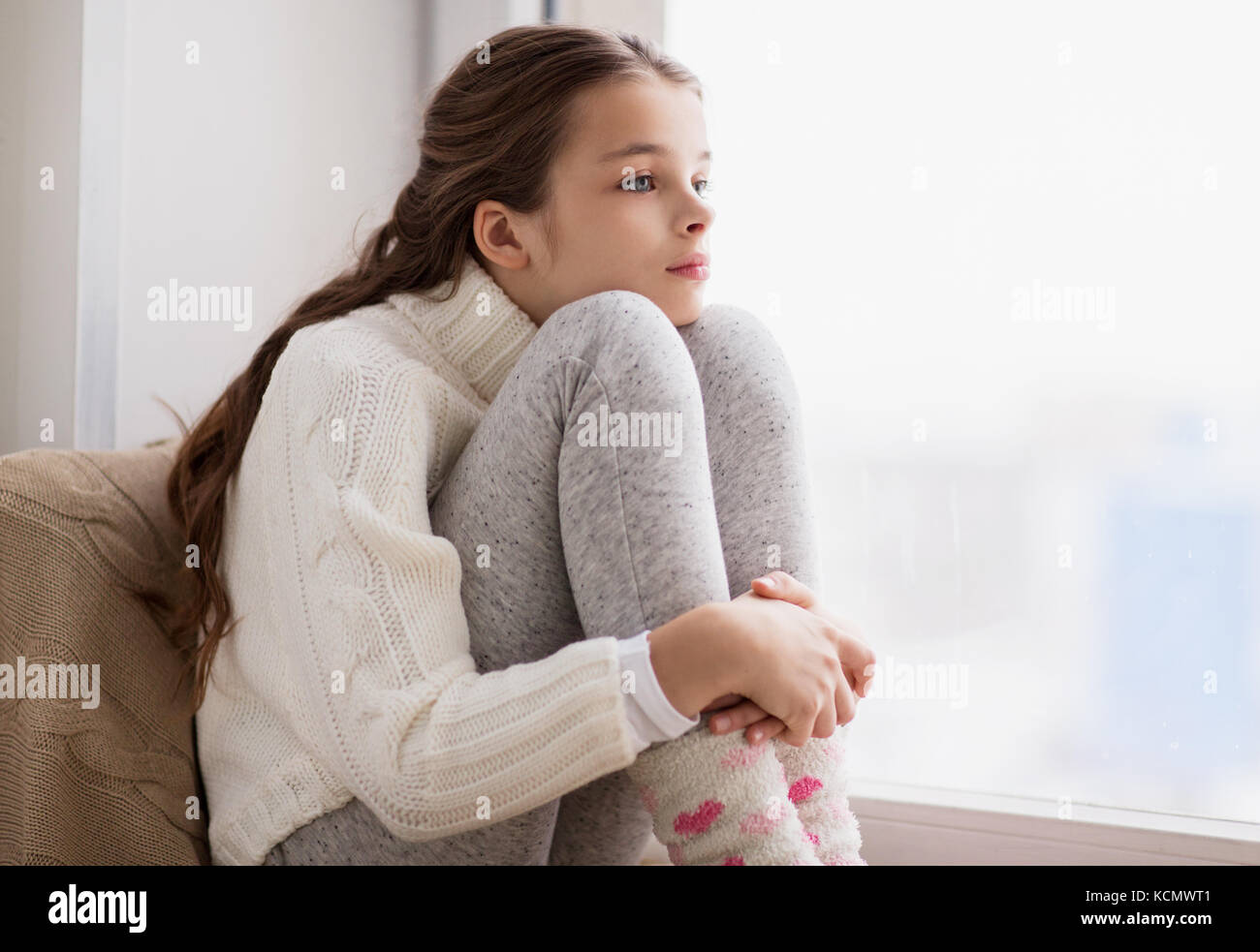 sad girl sitting on sill at home window in winter Stock Photo - Alamy