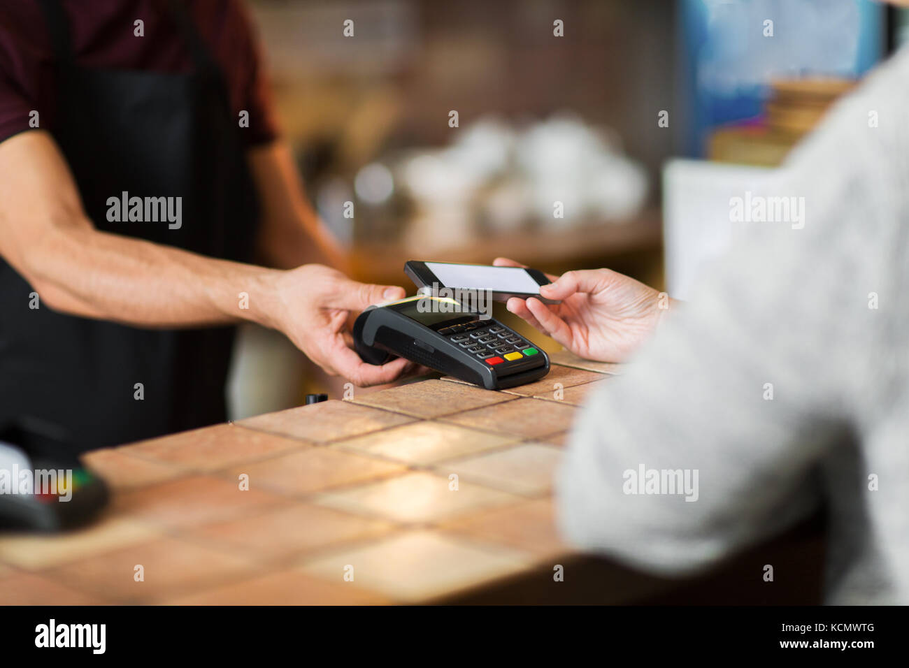 hands with payment terminal and smartphone at bar Stock Photo - Alamy