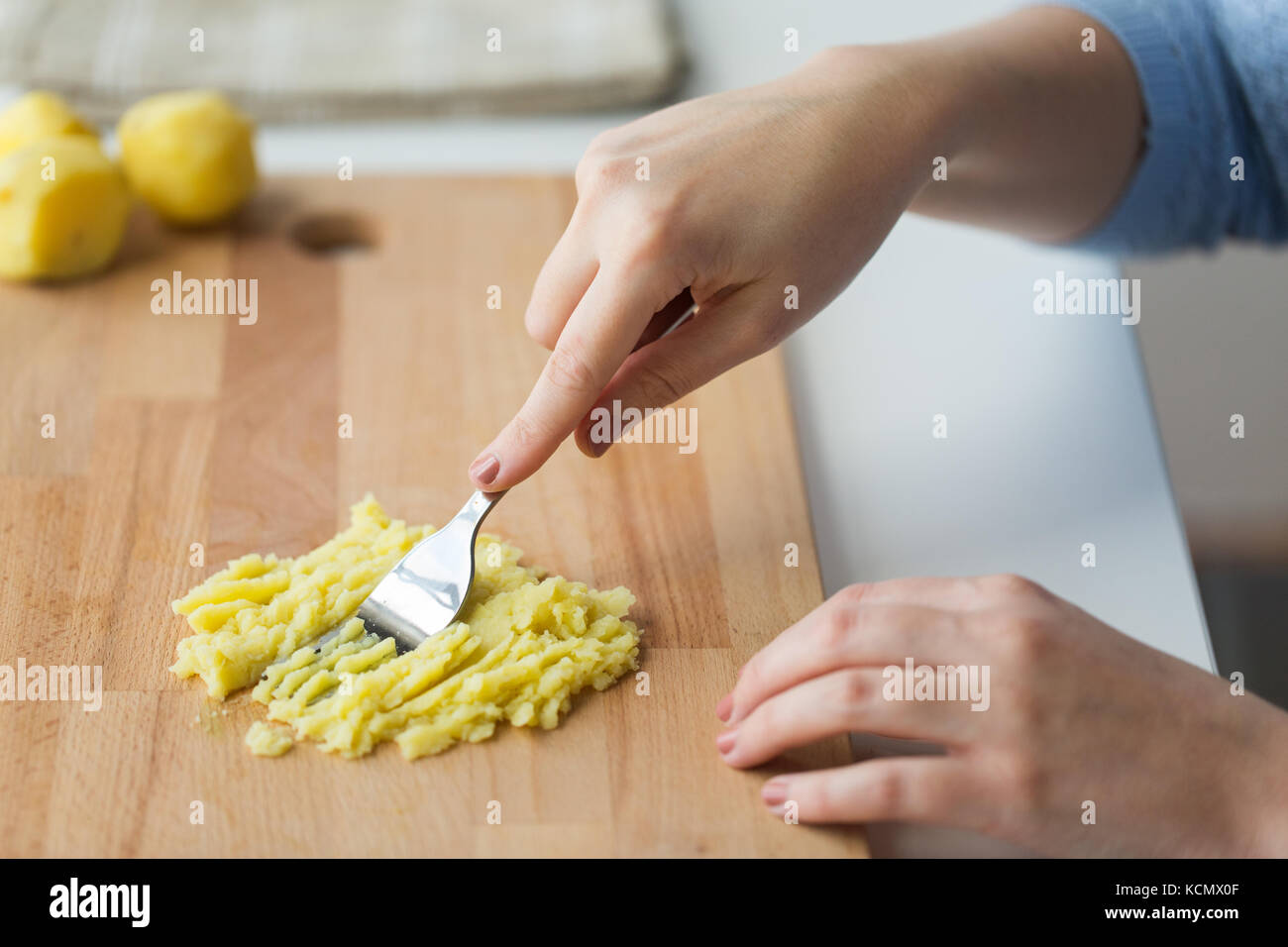 hand with fork making mashed potato on board Stock Photo - Alamy