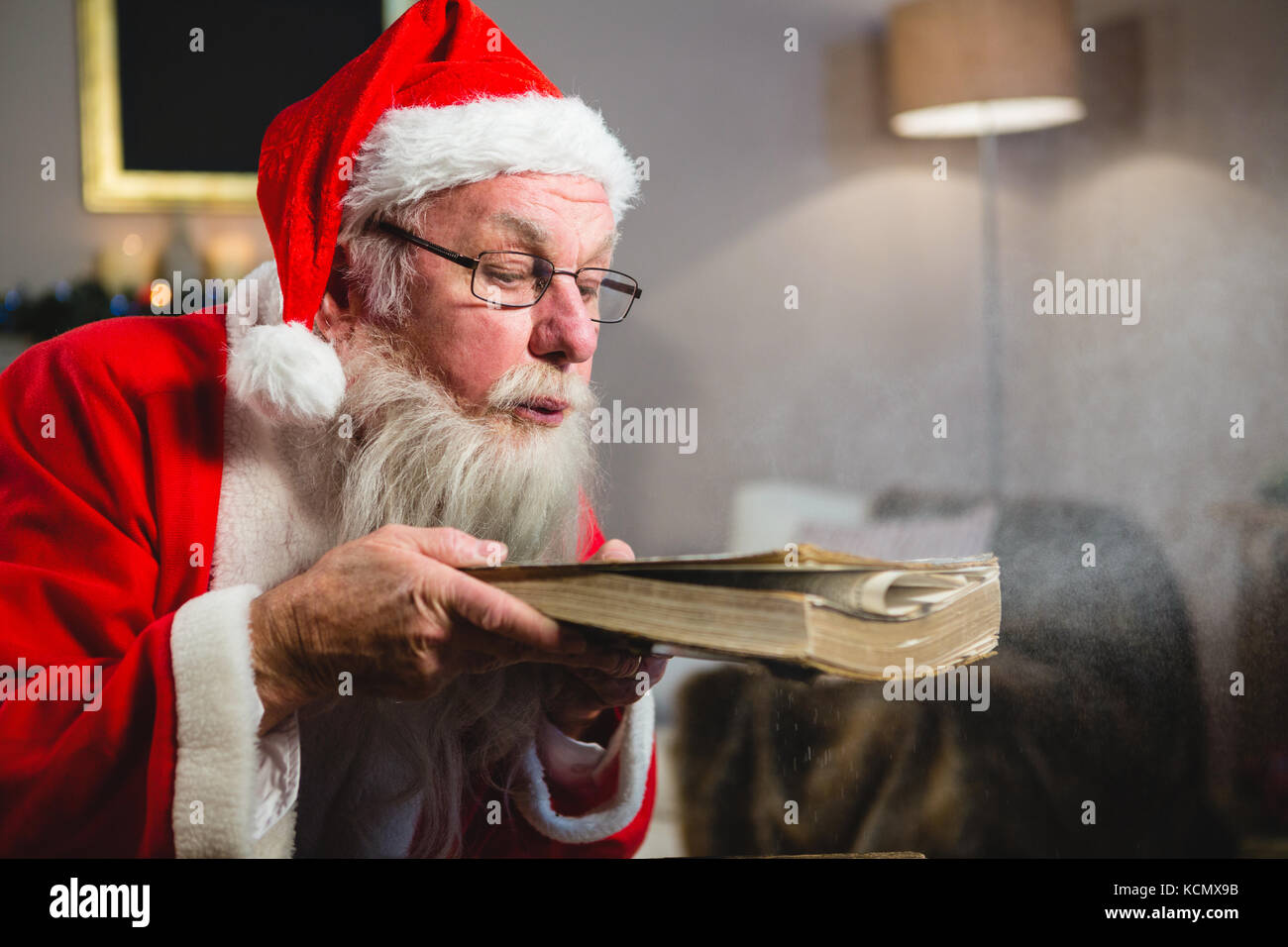 Santa Claus blowing dust from book at home Stock Photo - Alamy