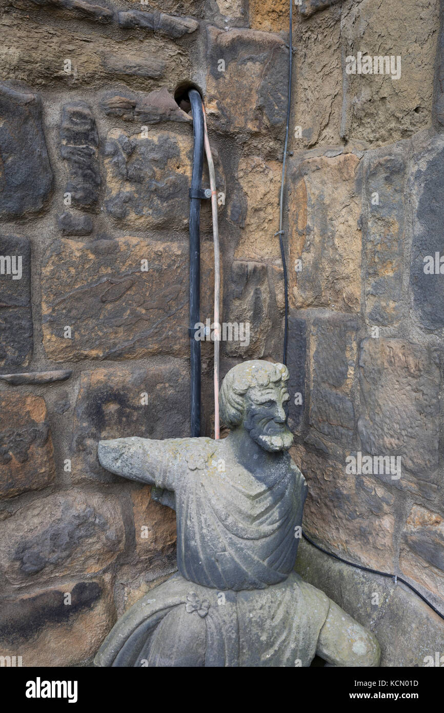 With contemporary electrical cables emerging from a wall above, a stone ...