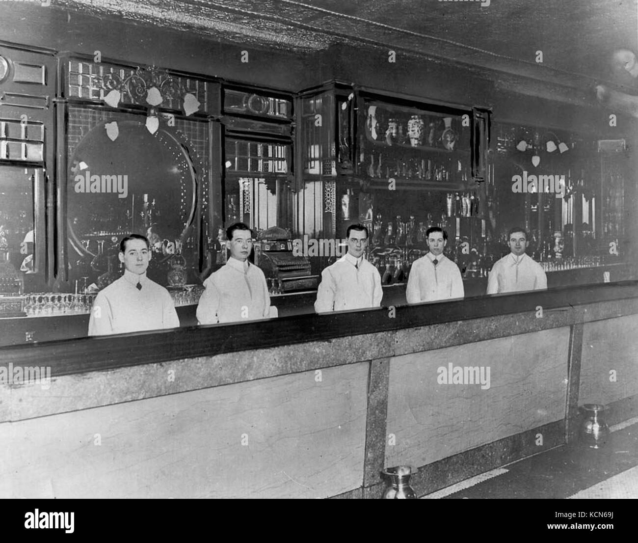 Five bartenders behind St. Charles Hotel bar Stock Photo - Alamy