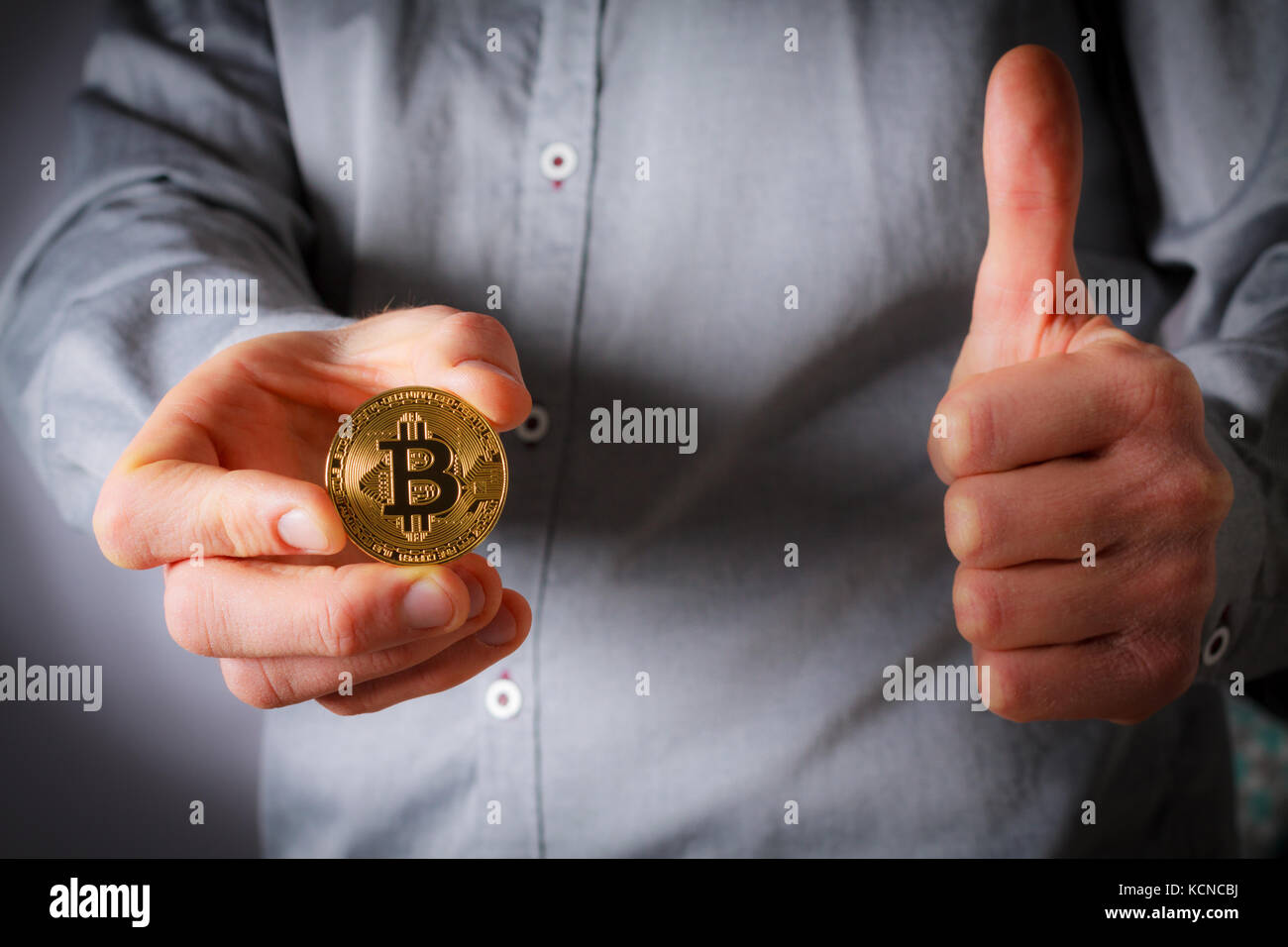 Hand hold bitcoin and next hand shows thumb up Stock Photo - Alamy