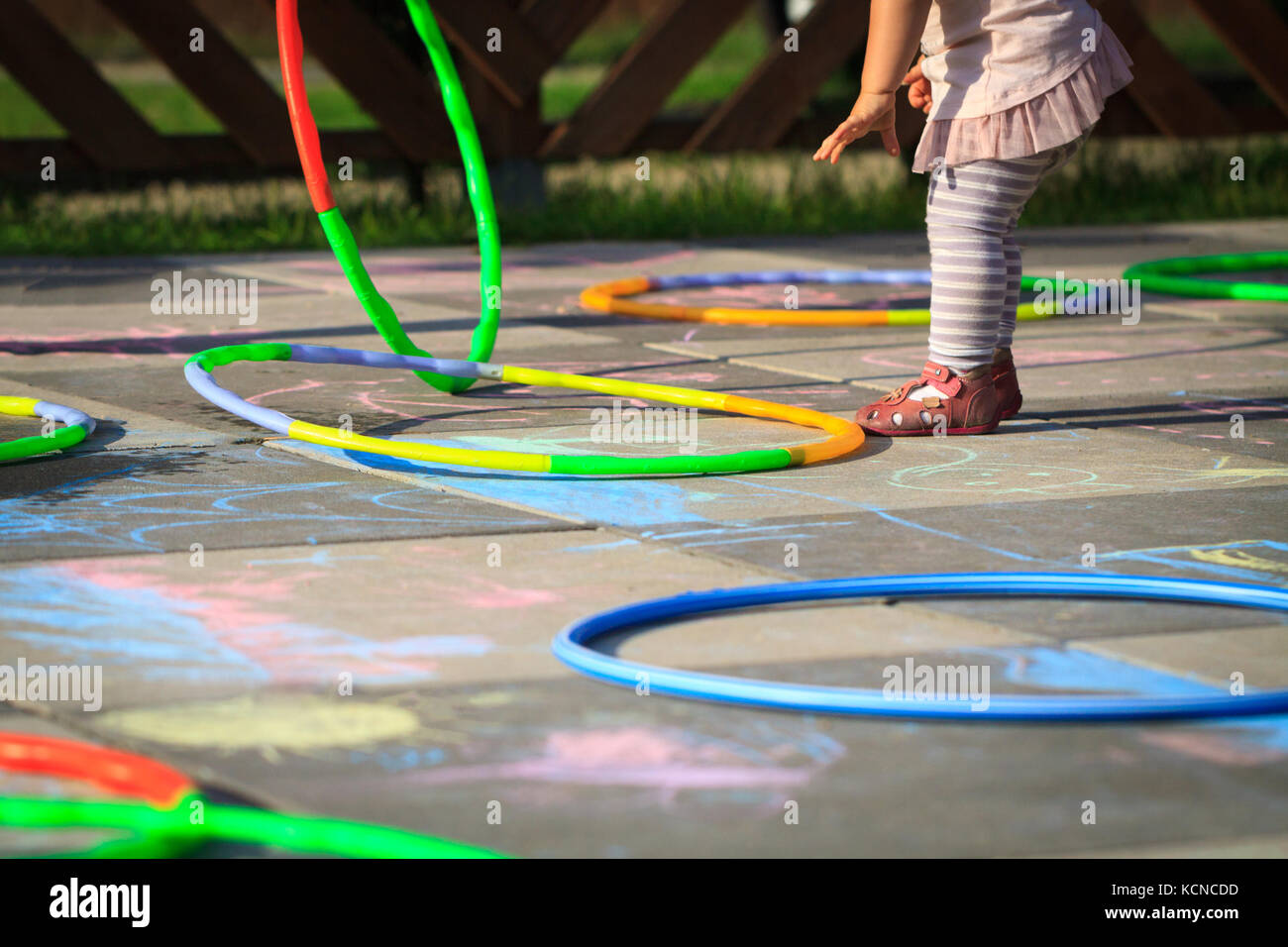 Small girl play hula hoops on playground scratched with chalk Stock ...