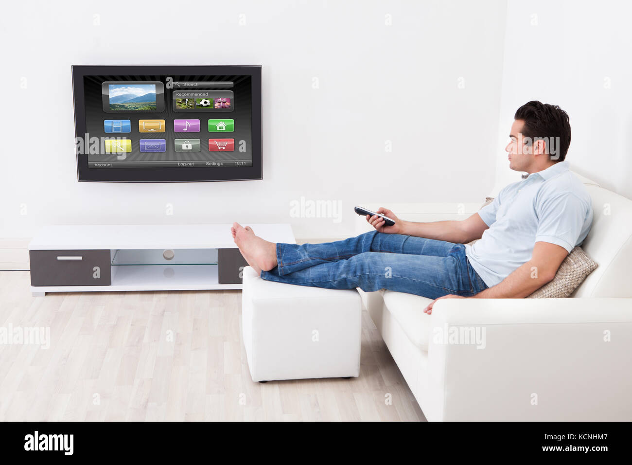 Young Man At Home Applying Setting Of Television Sitting On Couch Stock ...