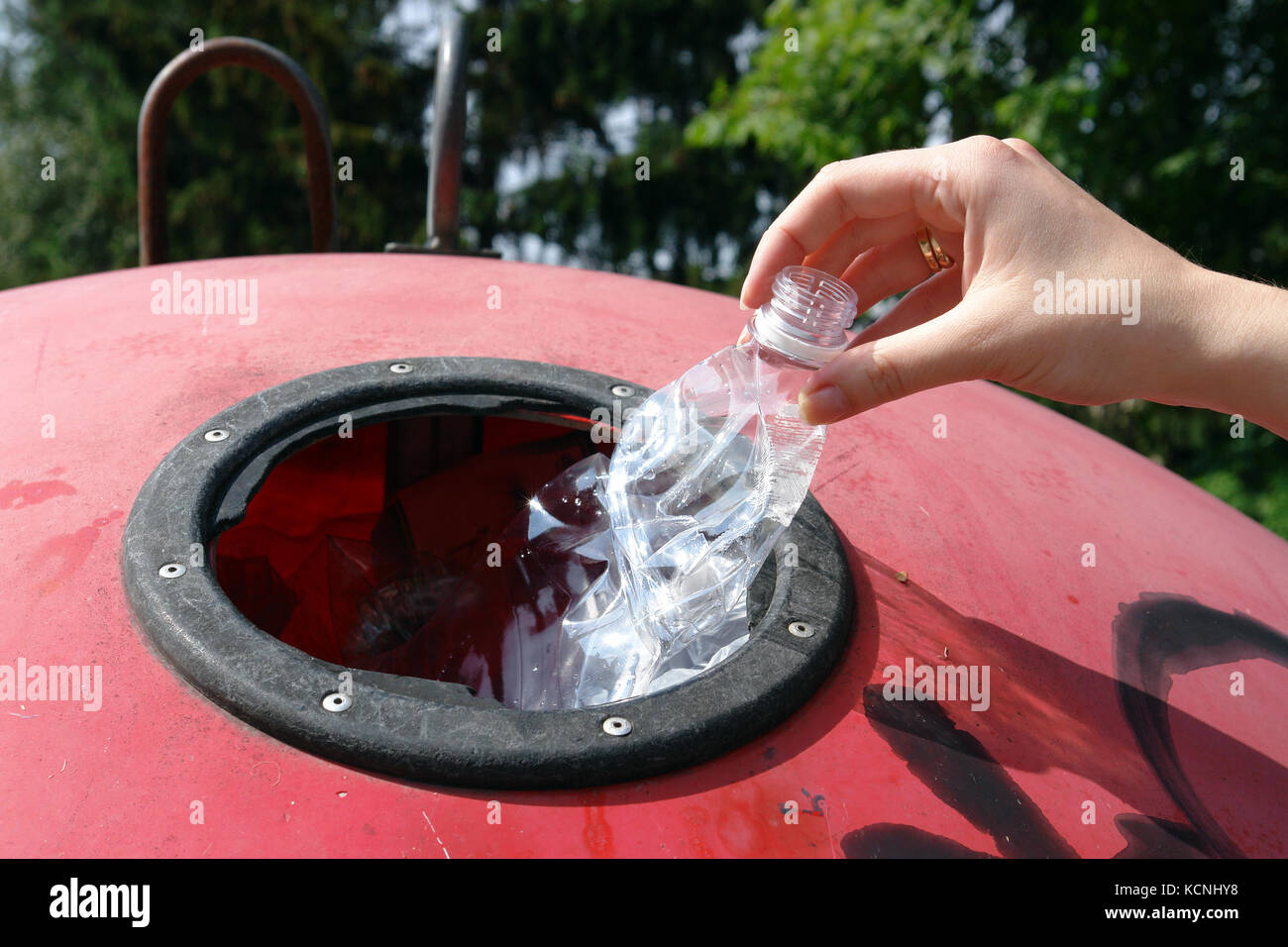 Female hand throwing empty plastic bottle into slot of waste separation ...