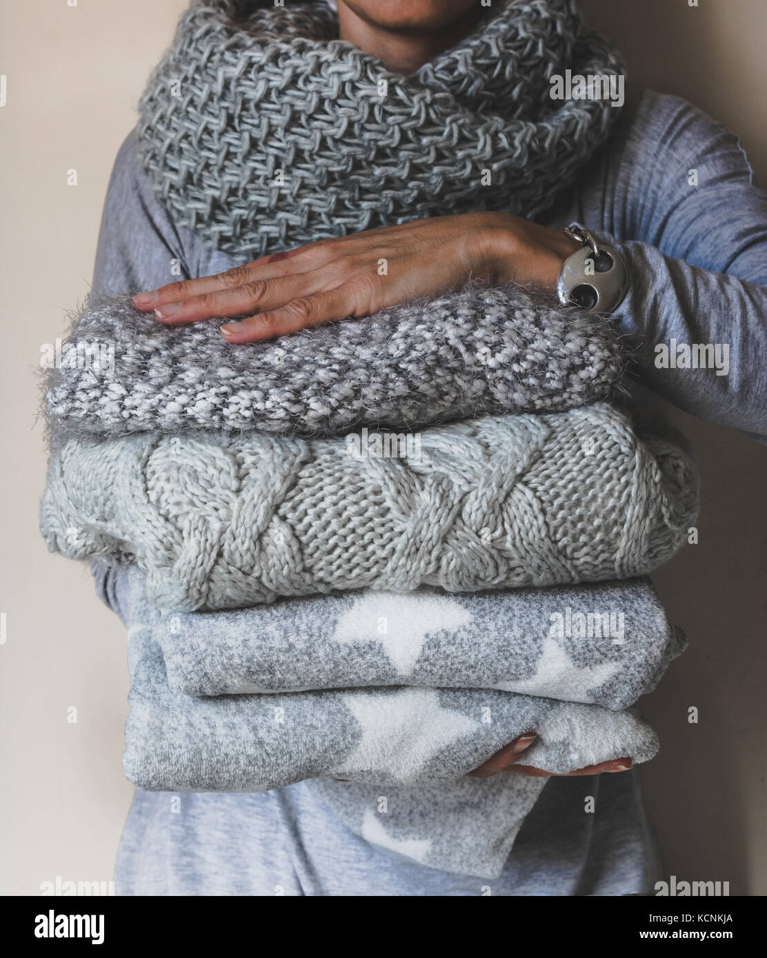 Woman holds a stack of woolen clothes, folded, winter sweaters, blue ...