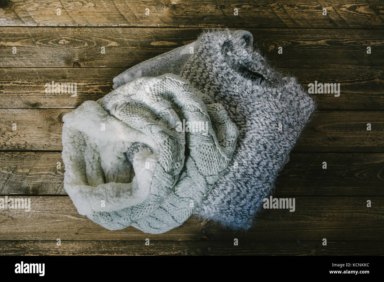 circular wool scarf and gray knit sweater over rustic wood, top view ...