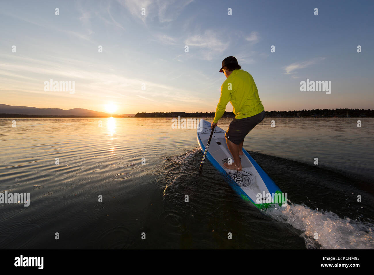 A Stand up paddleboarder launches into the sunset waters off of Goose ...