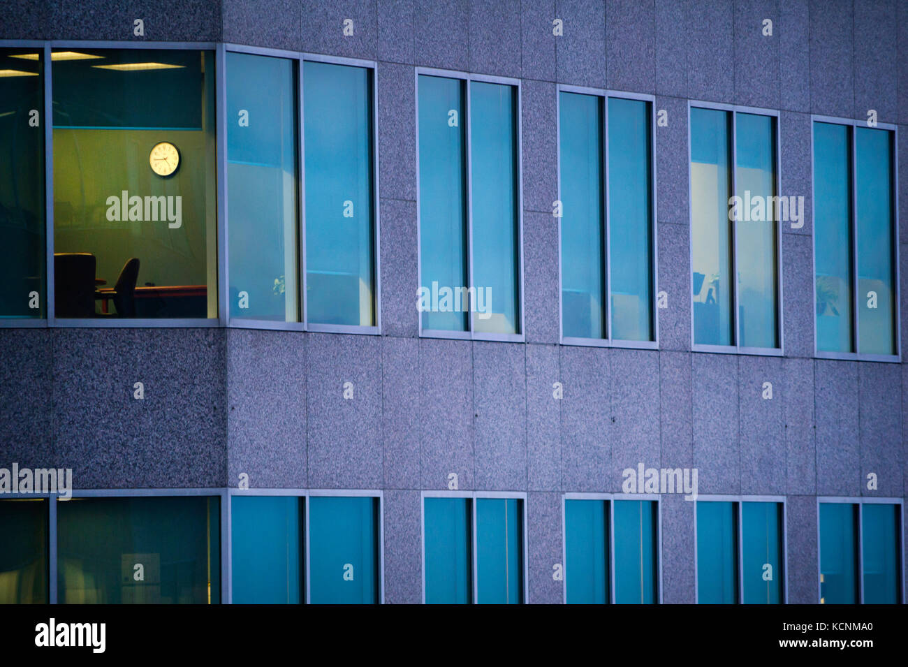 Clock in a window of an office building at night Stock Photo - Alamy