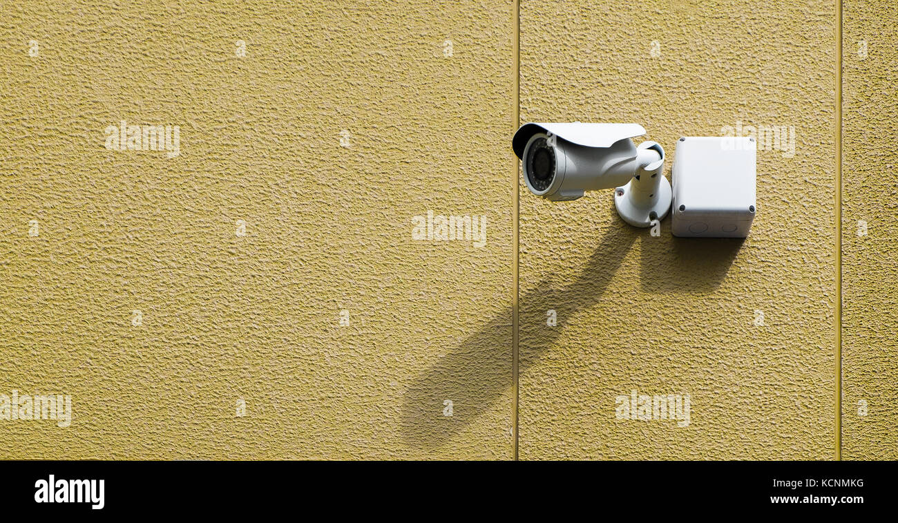 Infrared cctv camera on the exterior textured wall in yellow color with ...
