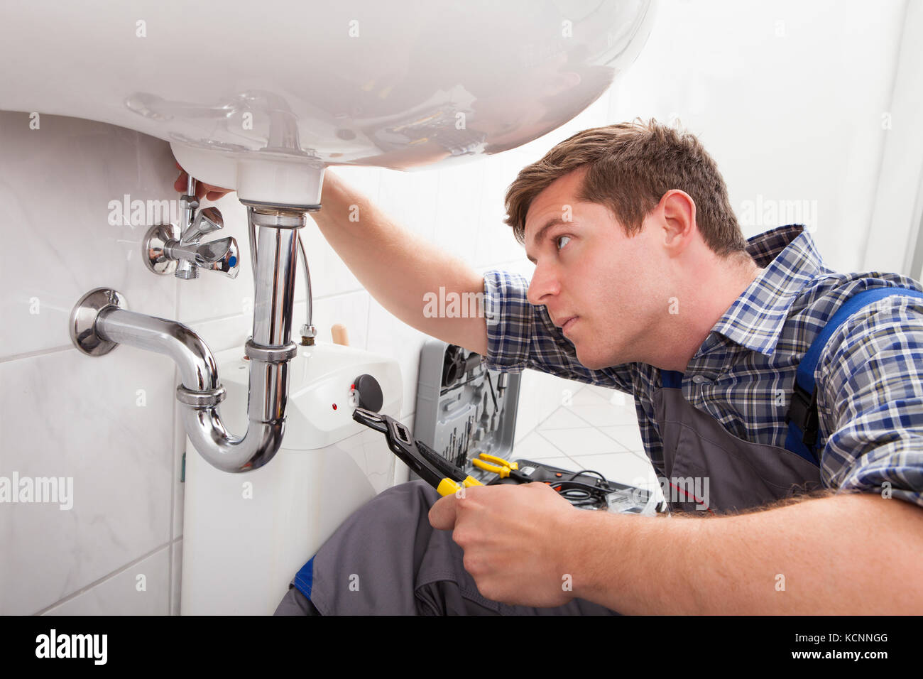 Portrait of male plumber fixing a sink in bathroom Stock Photo - Alamy
