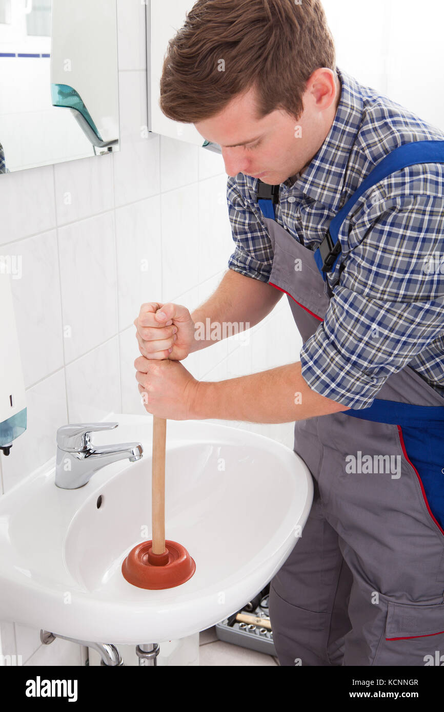 Portrait of male plumber pressing plunger in sink Stock Photo - Alamy