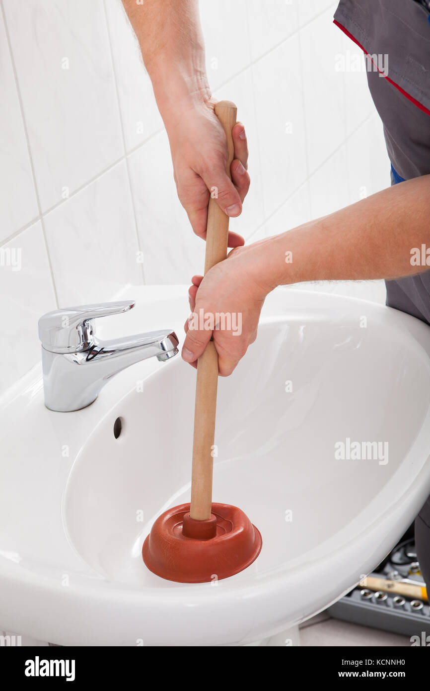 Portrait of male plumber pressing plunger in sink Stock Photo - Alamy