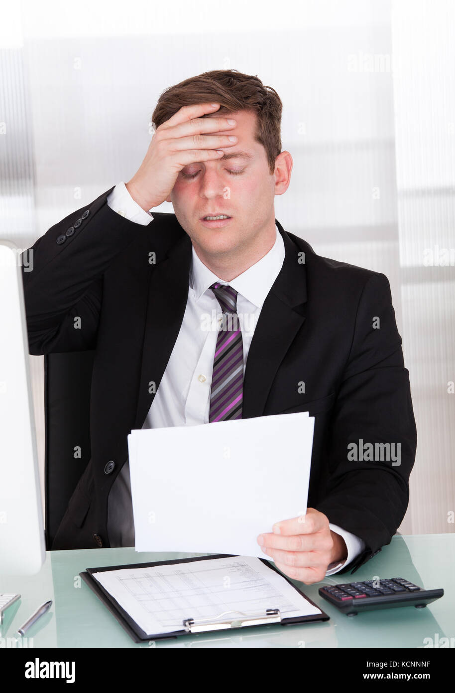 Portrait of Anxiety businessman sitting in office holding paper Stock ...