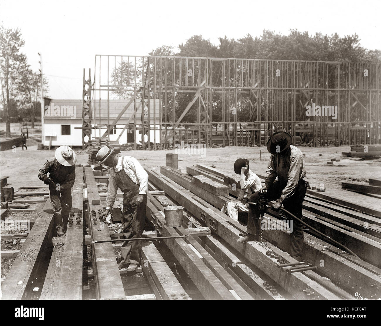 Carpenters drilling holes and placing bolts in timbers during ...