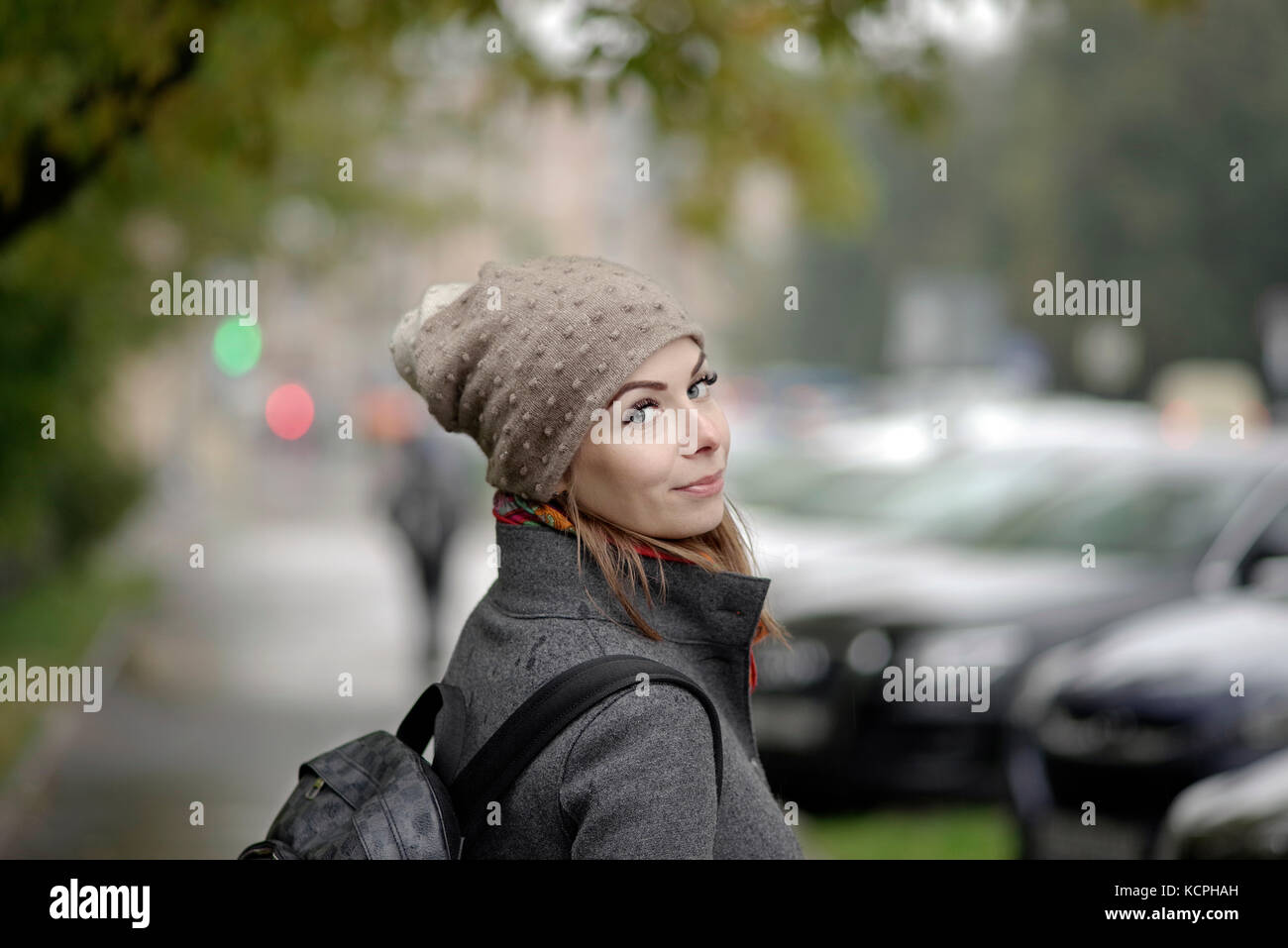 Young woman with a happy face posing in a rainy day, the traffic lights ...