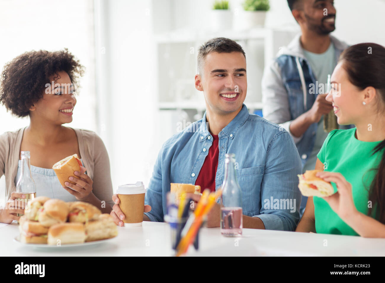 happy friends or team eating at office party Stock Photo - Alamy