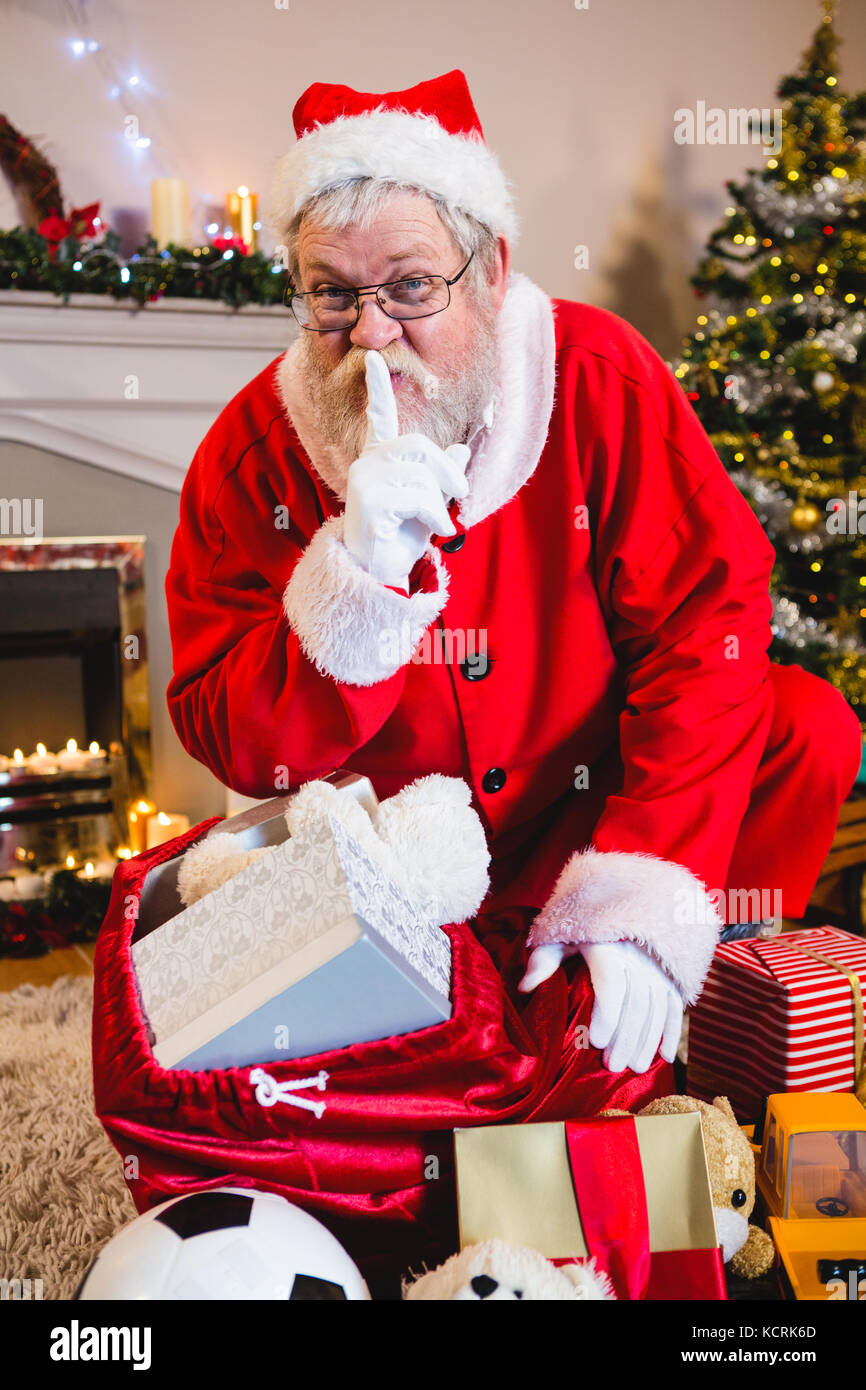 Portrait of santa claus with finger on lips in living room during ...