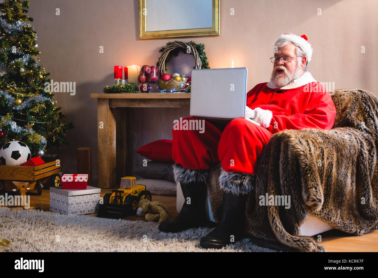 Santa claus sitting and using laptop at home Stock Photo - Alamy