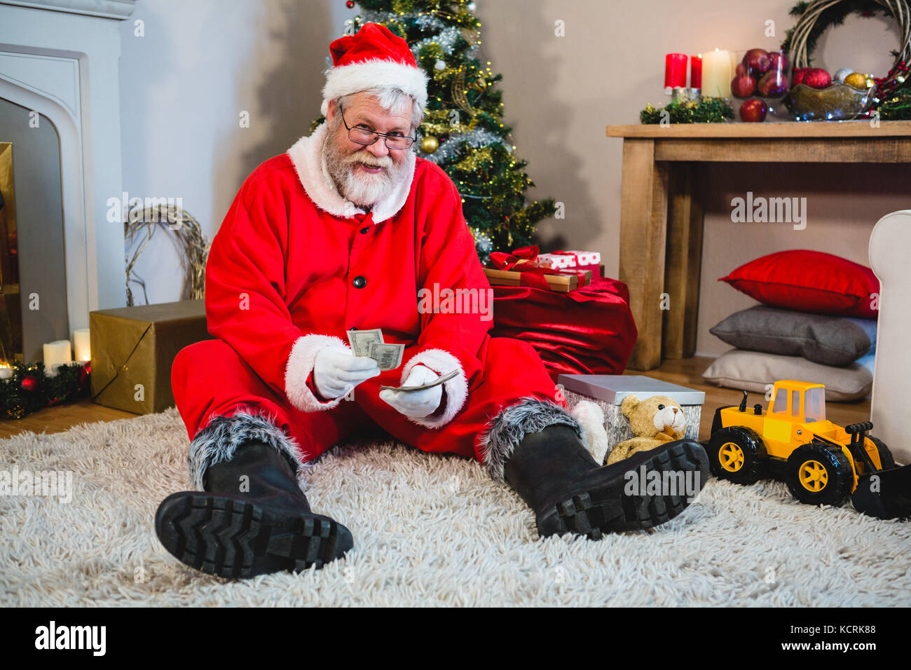 Portrait of santa claus sitting on the floor and counting cash at home ...
