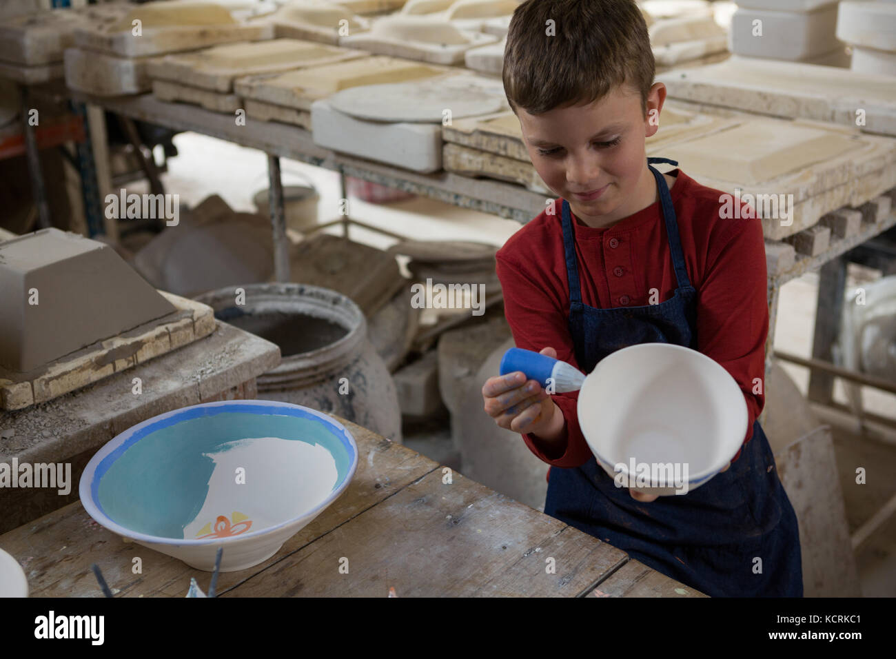 Boy decorating bowl with water color in pottery workshop Stock Photo ...