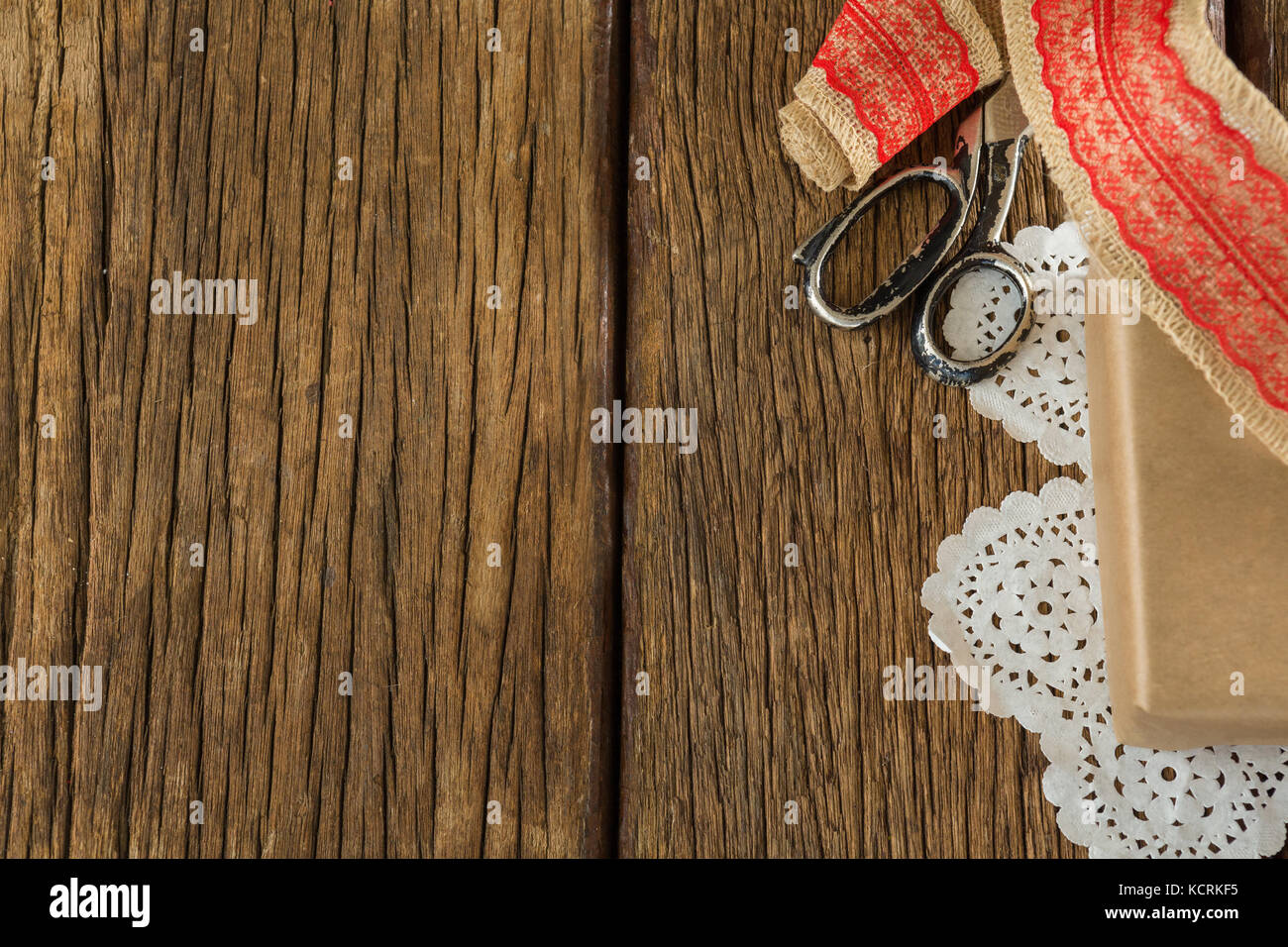 Wrapped gift, ribbon and scissors on wooden plank during christmas time ...