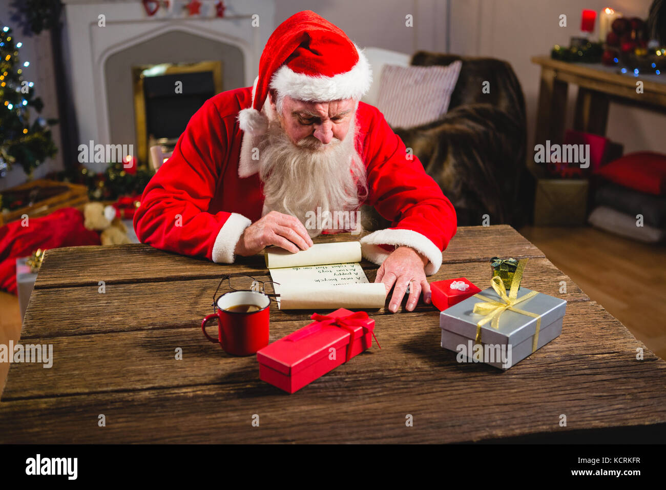 Santa Claus reading scroll in living room at home Stock Photo - Alamy