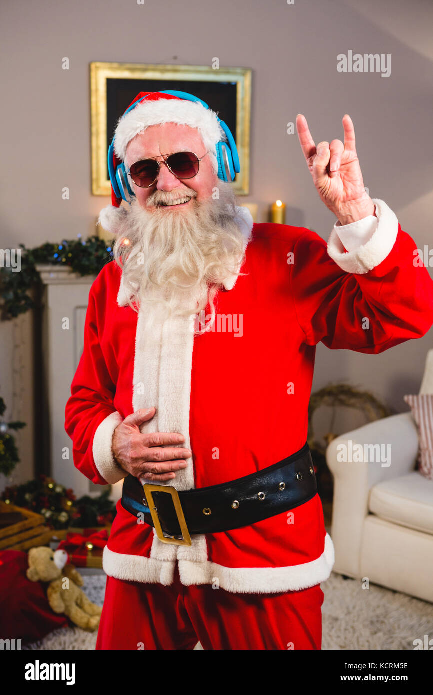 Smiling santa claus listening to music on headphones at home Stock ...