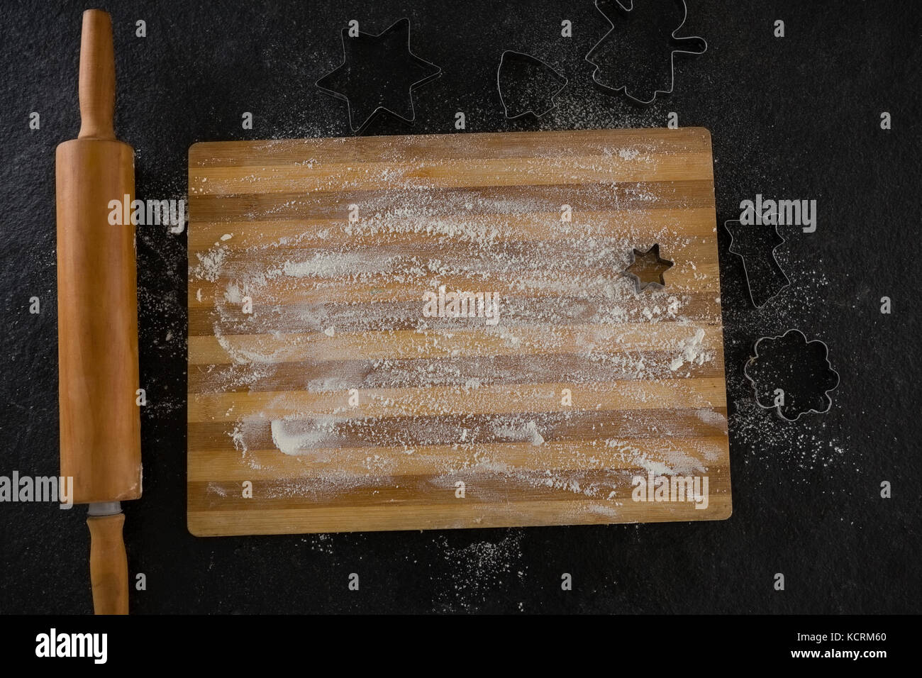 Overhead of flour on chopping board with various cookie cutters and ...