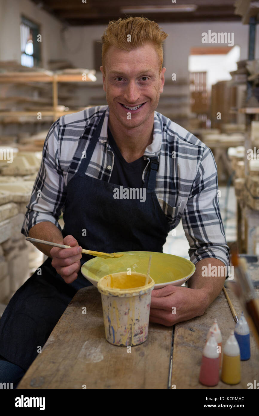 Portrait of male potter painting a bowl in pottery workshop Stock Photo ...
