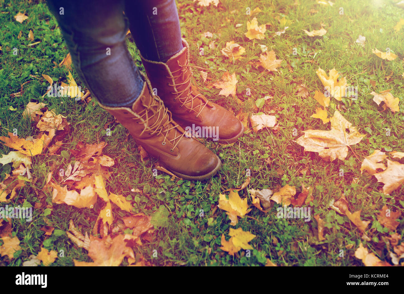 female feet in boots and autumn leaves on grass Stock Photo - Alamy