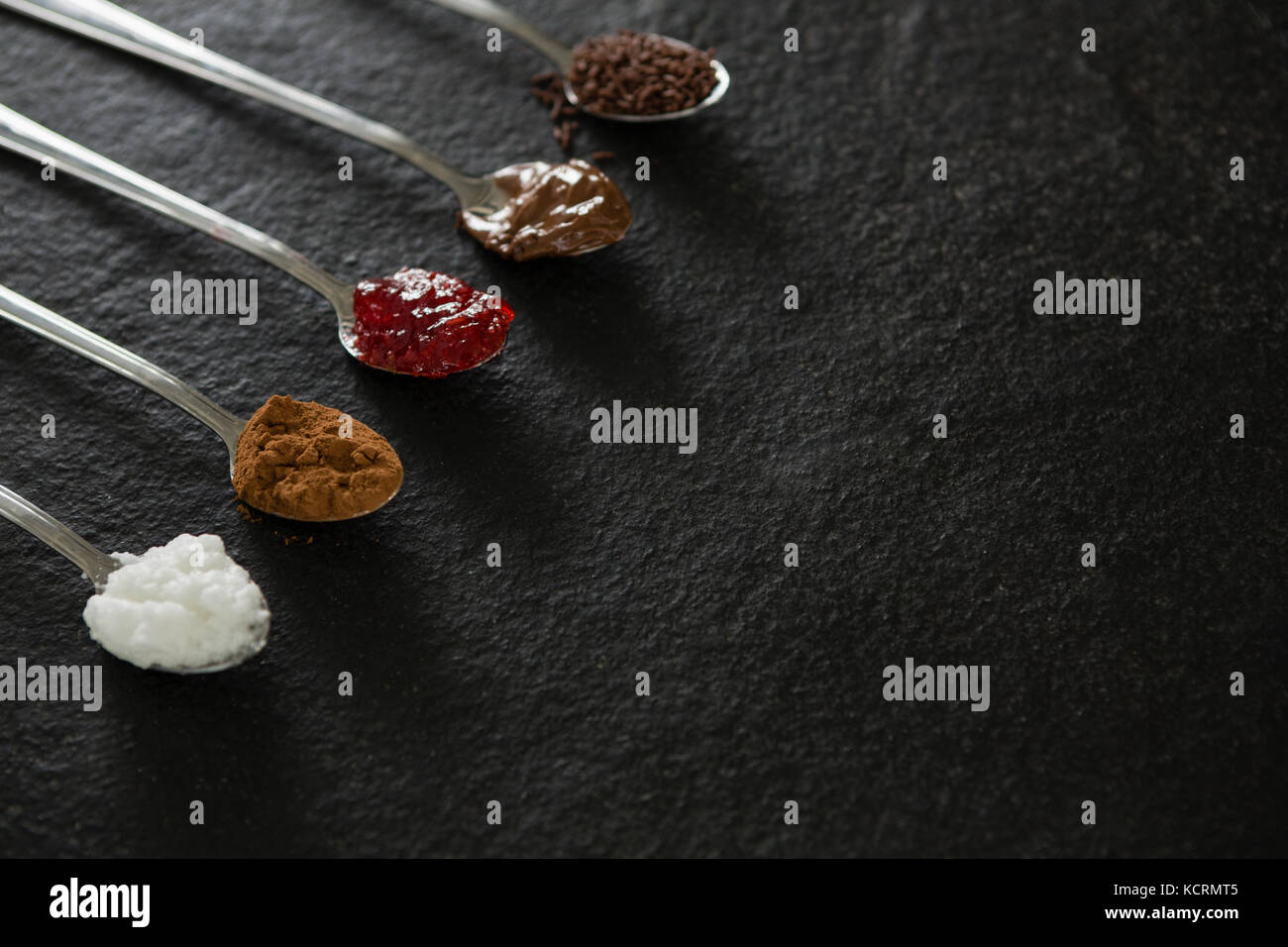 Various cookies seasoning ingredients in spoon on black background ...