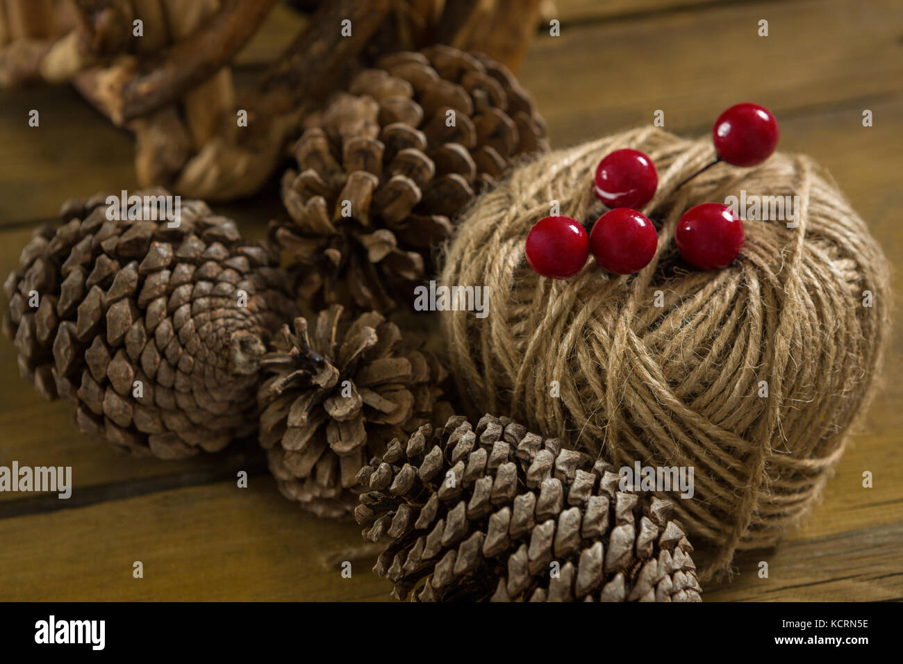 High angle view of pine cones with thread spool with push pin on table ...