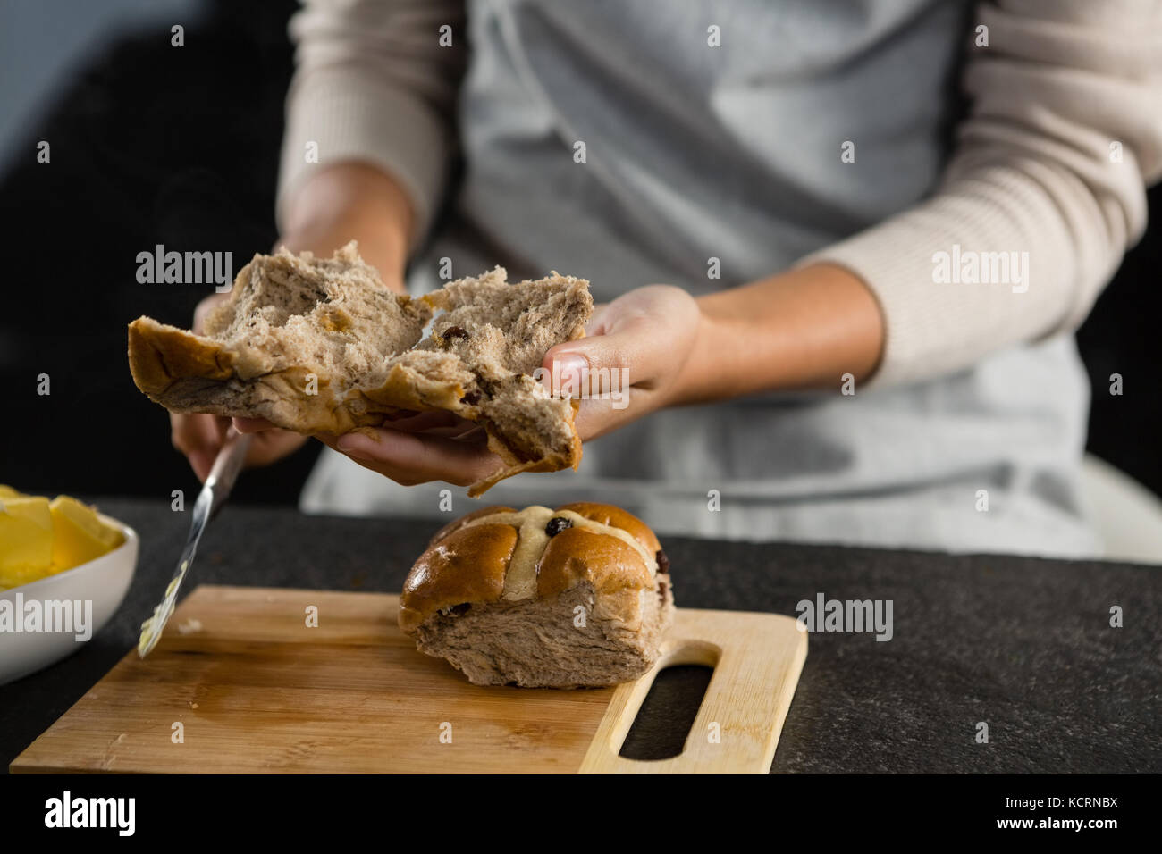 Mid section of woman cutting open a brown bun Stock Photo - Alamy