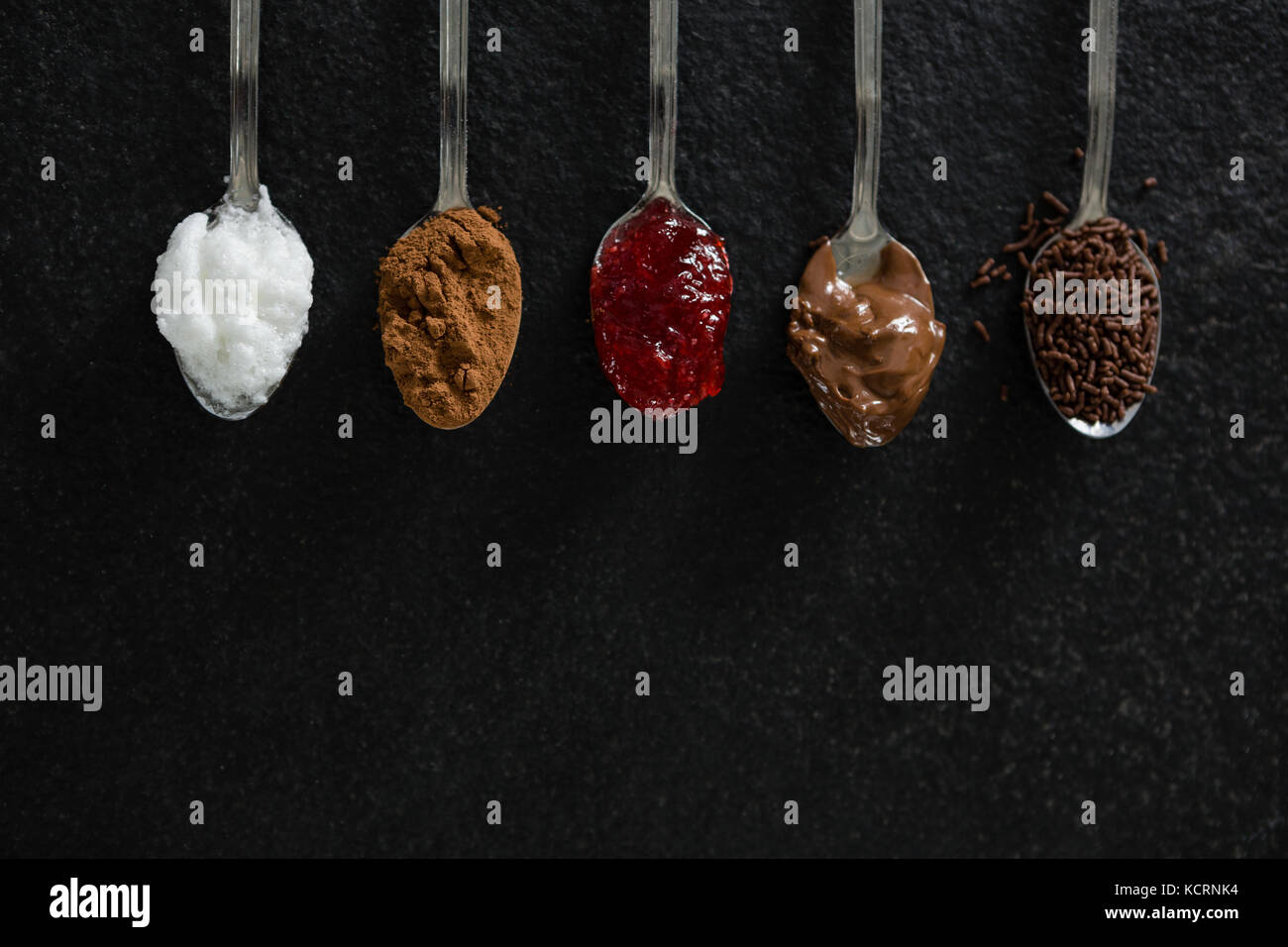 Various cookies seasoning ingredients in spoon on black background ...