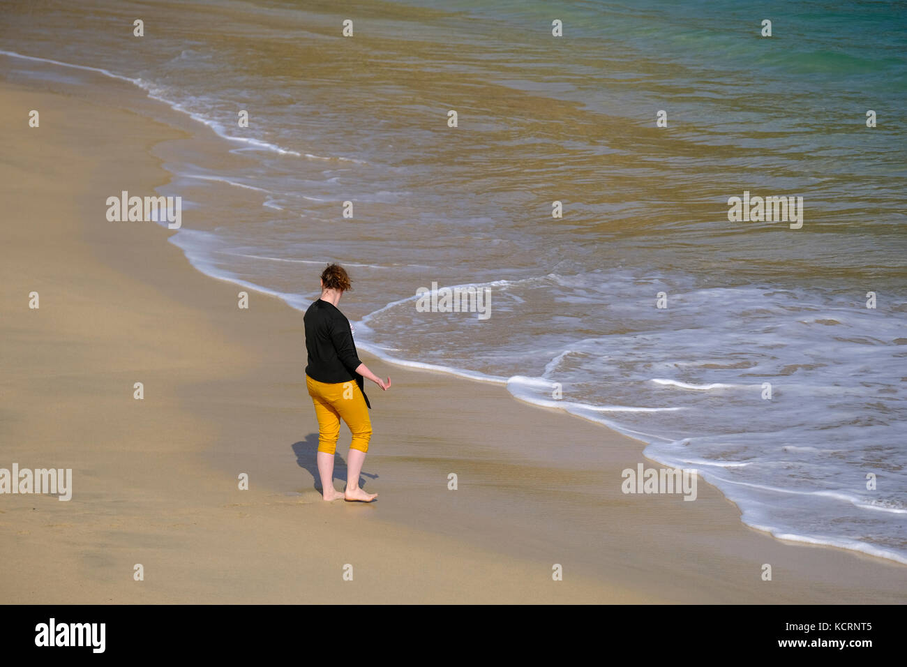 Woman standing on the beach watching the tide come in Stock Photo - Alamy