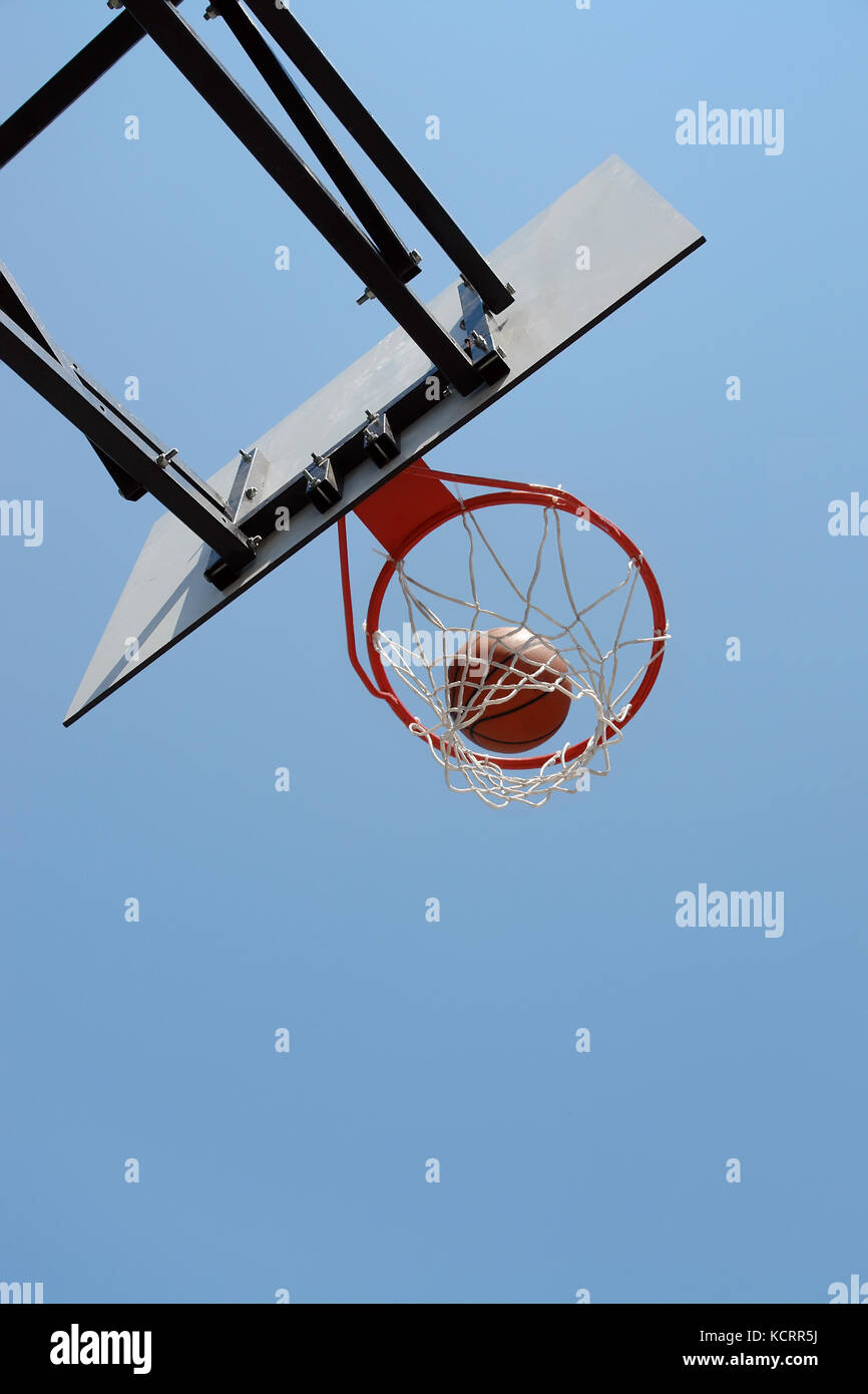 Basketball hitting the backboard net against clear blue sky Stock Photo ...