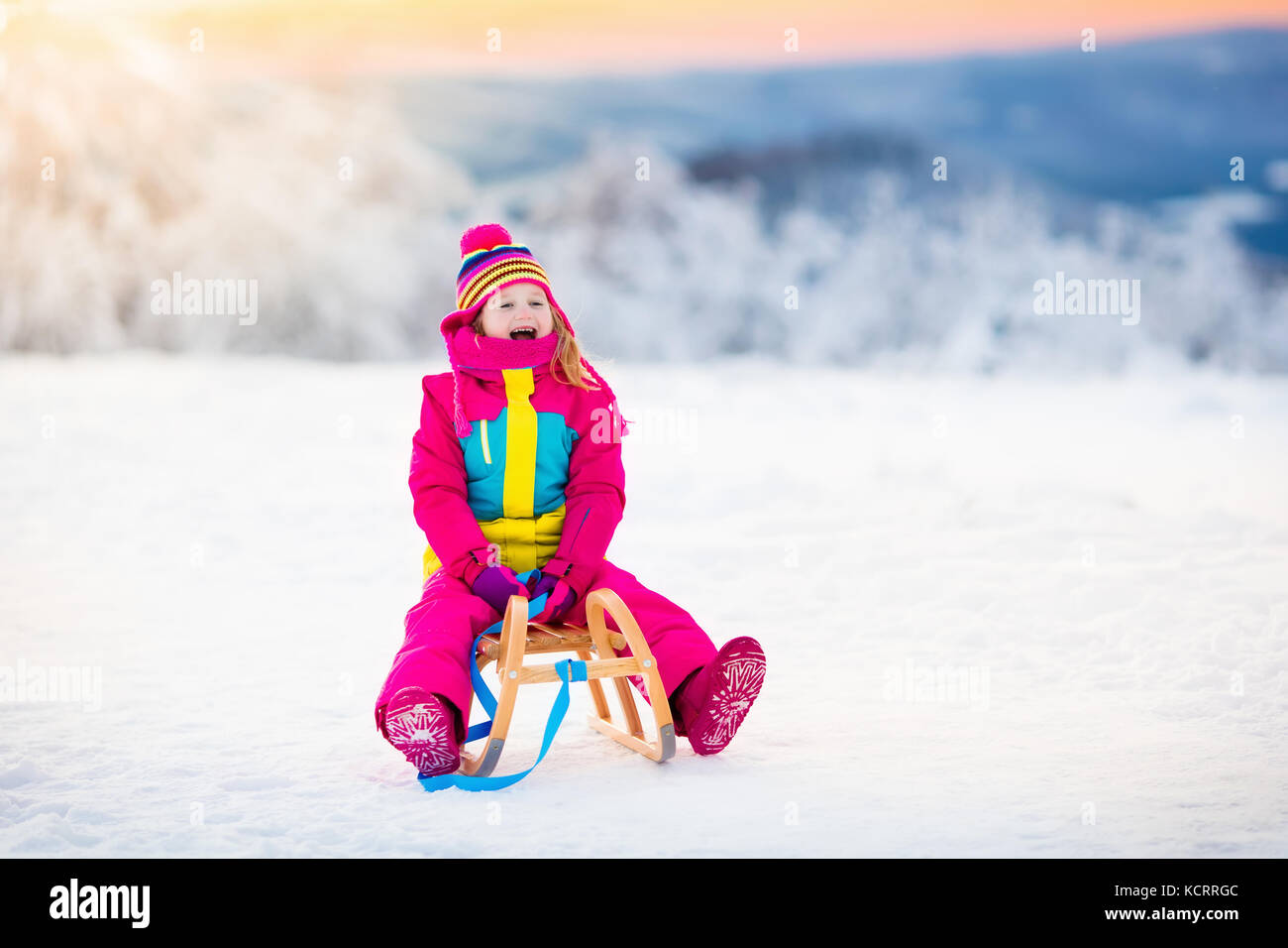 Little girl enjoying a sleigh ride. Child sledding. Toddler kid riding ...